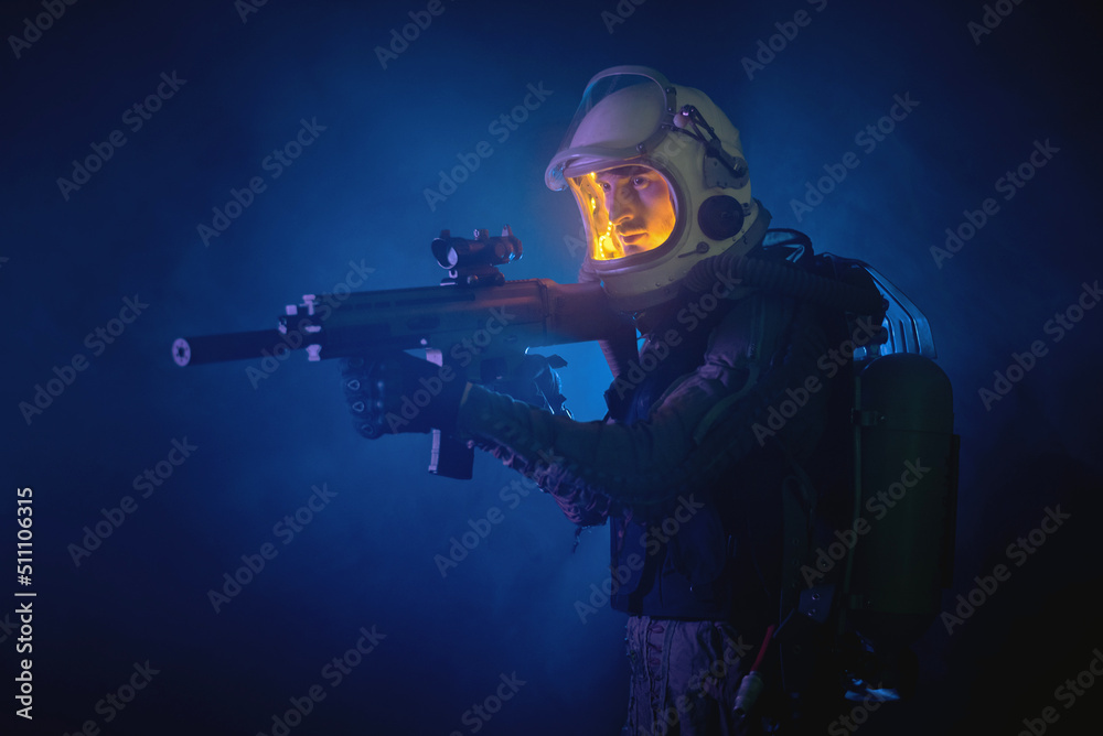 Spaceman or star trooper in the helmet and with rifle in the blue smoke ...