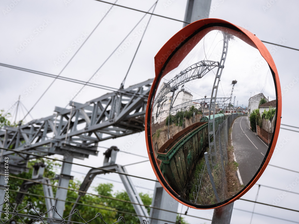 Wagons and train tracks reflected in a mirror located between a road ...