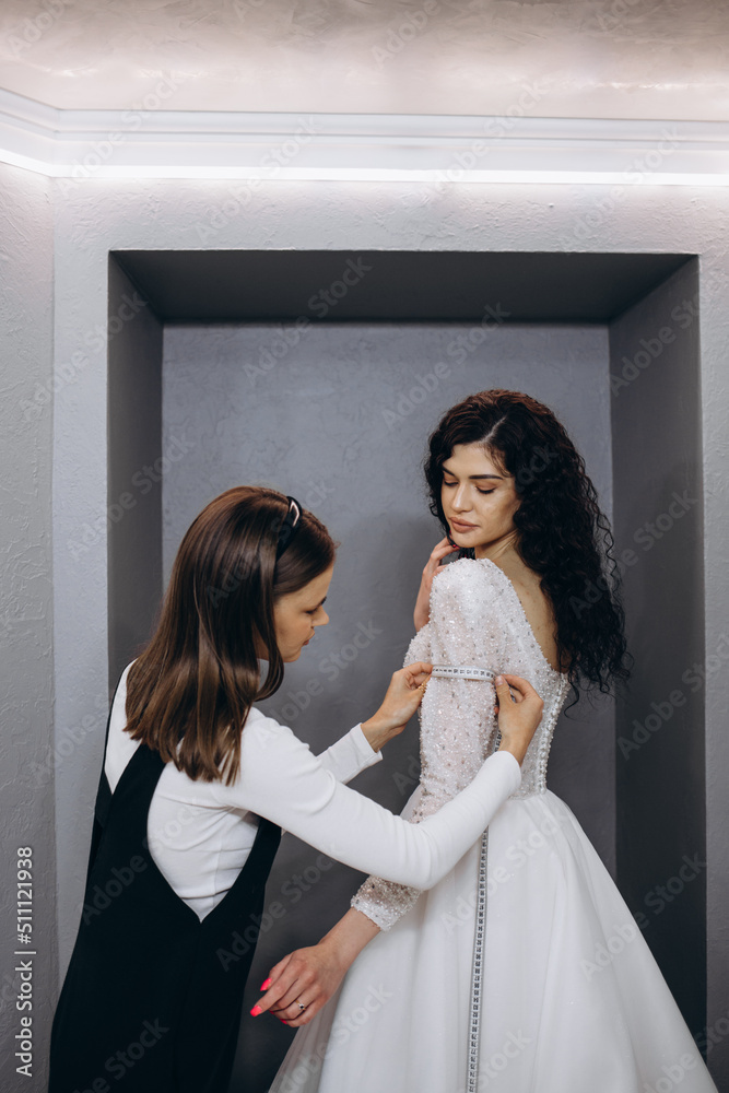 Female making adjustment to wedding gown in fashion designer studio ...