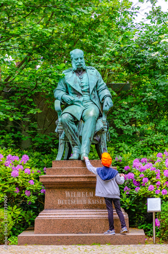 Boy touching the statue of Kaiser Wilhelm in the Westfalen park ...