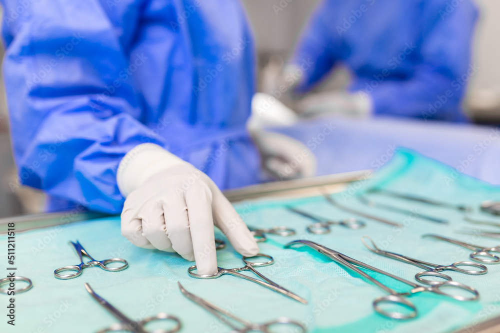 Nurse hand taking surgical instrument for group of surgeons at ...