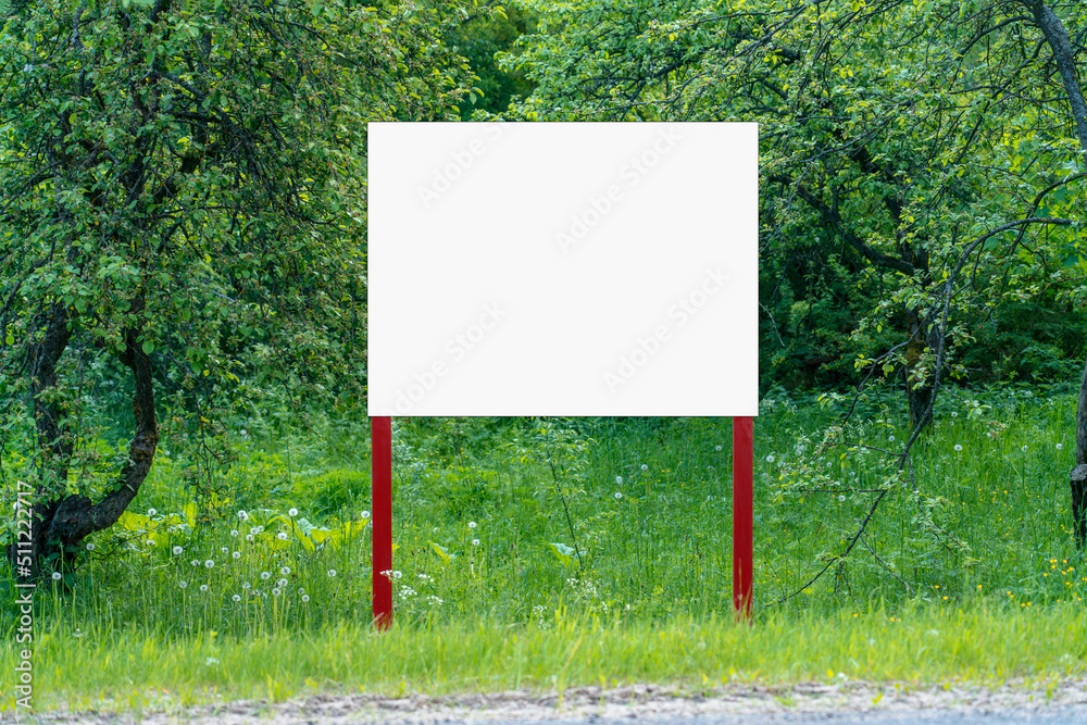White empty signboard with space for mockup stands on summer garden. Information blank banner on ...