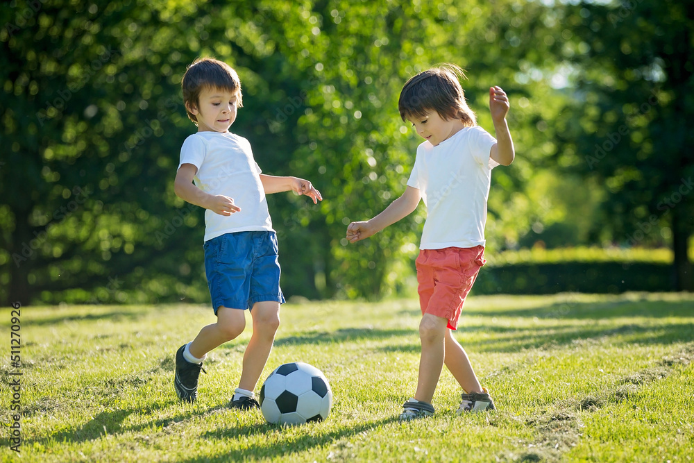 Two cute little kids, playing football together, summertime. Children ...
