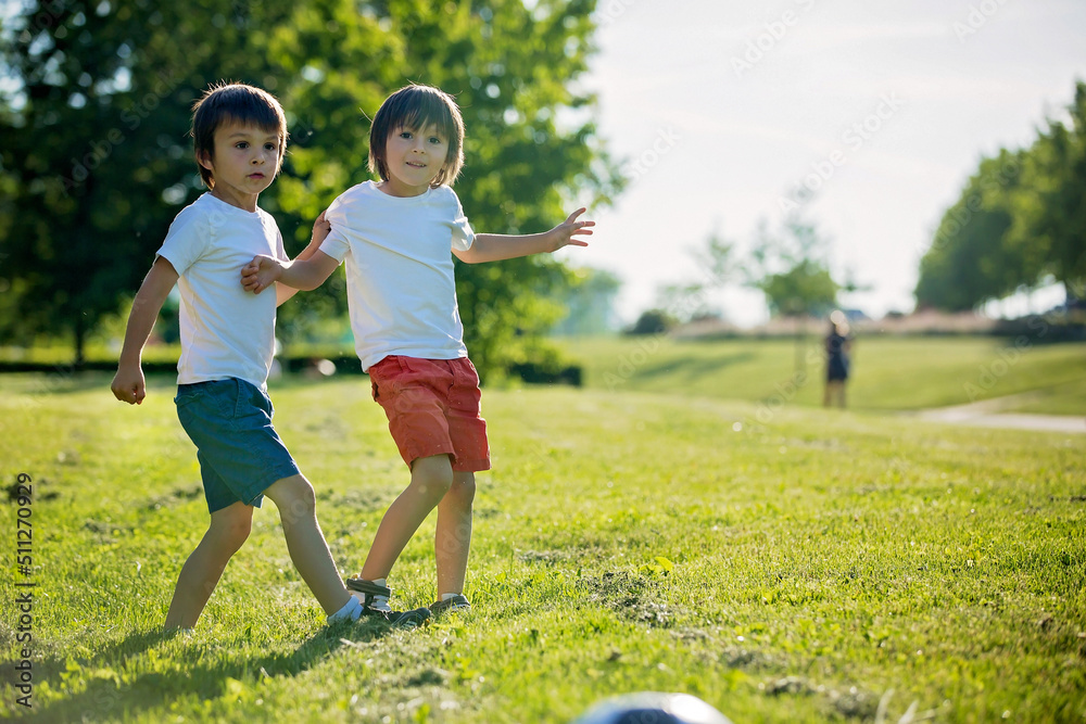 Two cute little kids, playing football together, summertime. Children ...