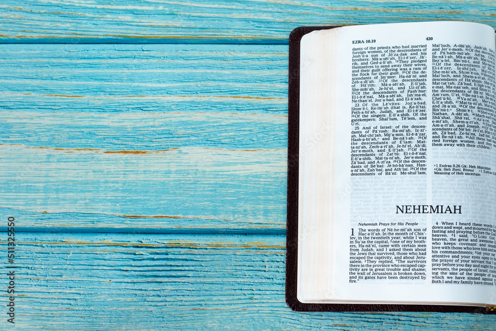 Nehemiah open Holy Bible Book on a blue wooden table background with ...