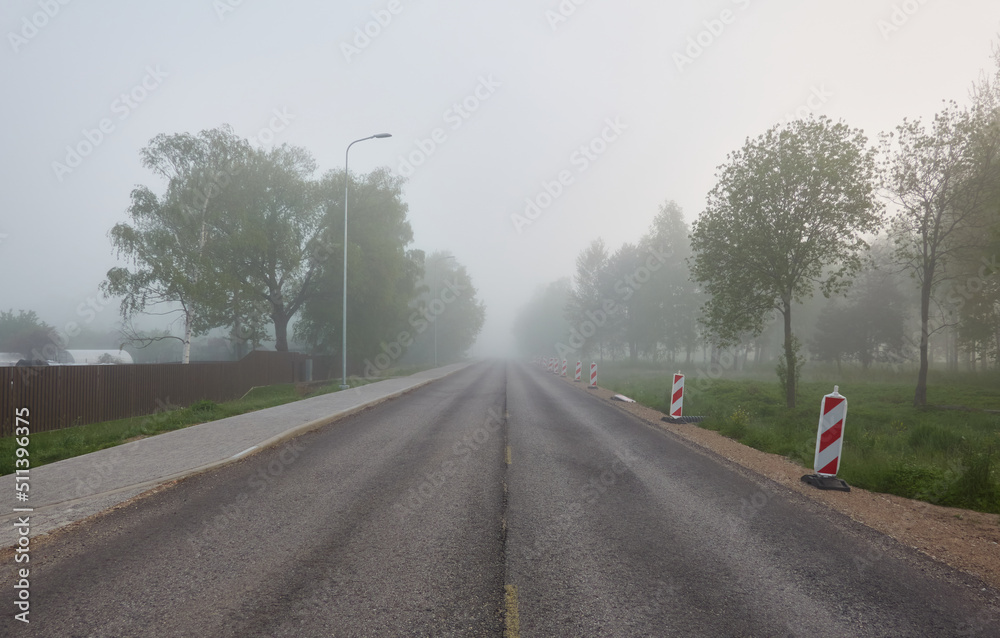 An empty new asphalt road (hghway) in a thick fog. Red and white ...