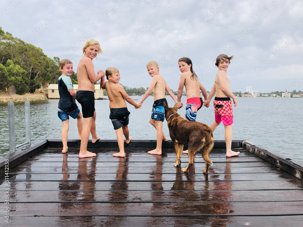 Six kids holding hands smiling at camera, about to jump of a pier Stock Photo | Adobe Stock