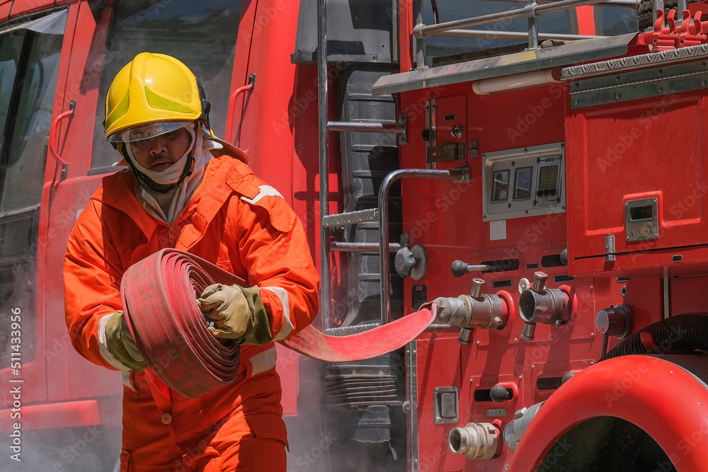Firefighters drag fire hoses connected to fire truck hoses. in ...
