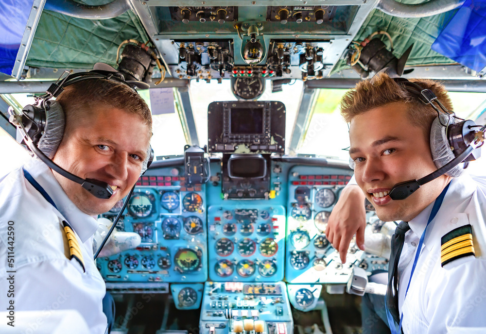 Happy pilots are smiling in the cockpit of an airplane. Greetings from ...