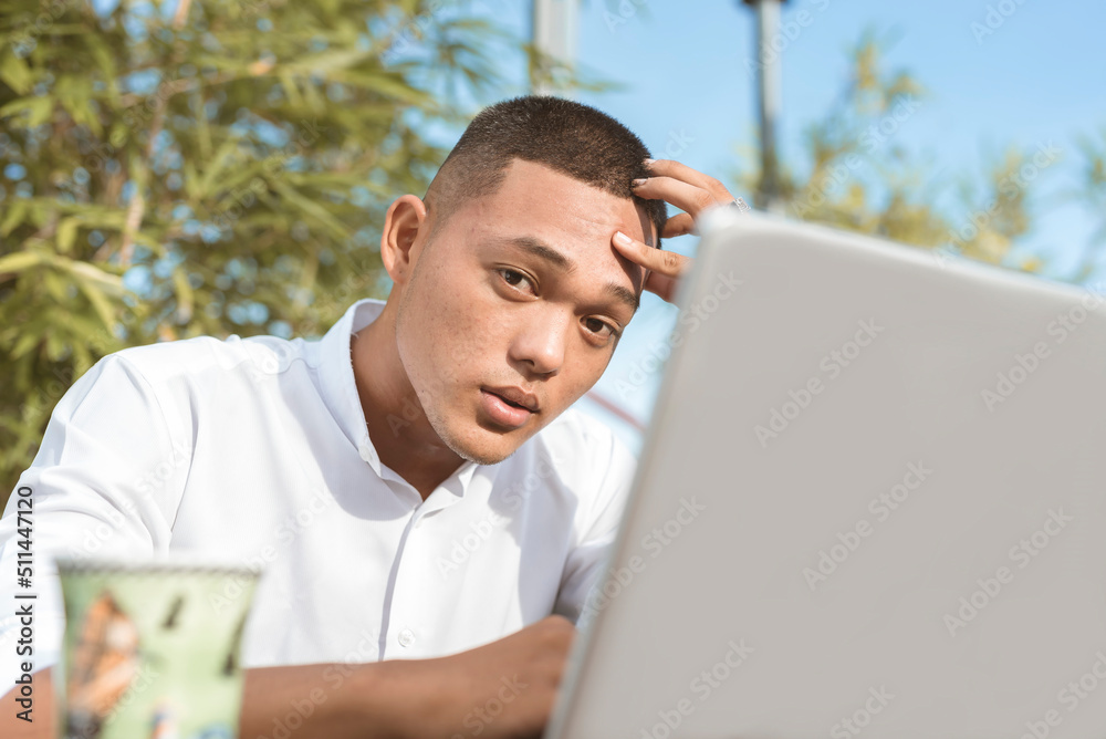 A Filipino male data analyst feeling stressed while working remotely at ...