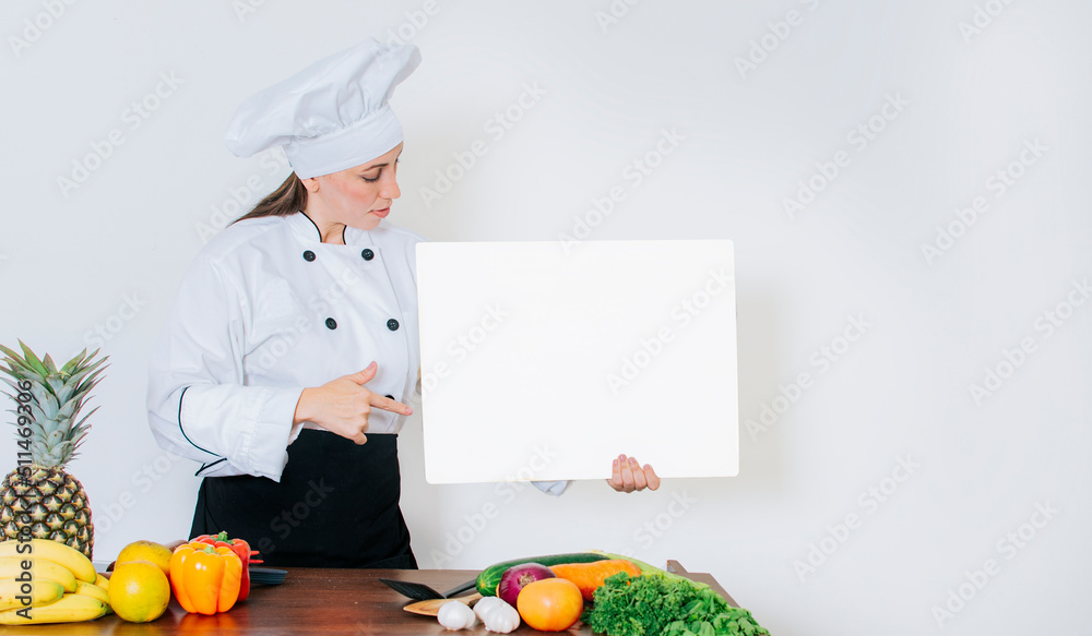 Chef woman with vegetables at table holding blank menu. Girl chef in ...
