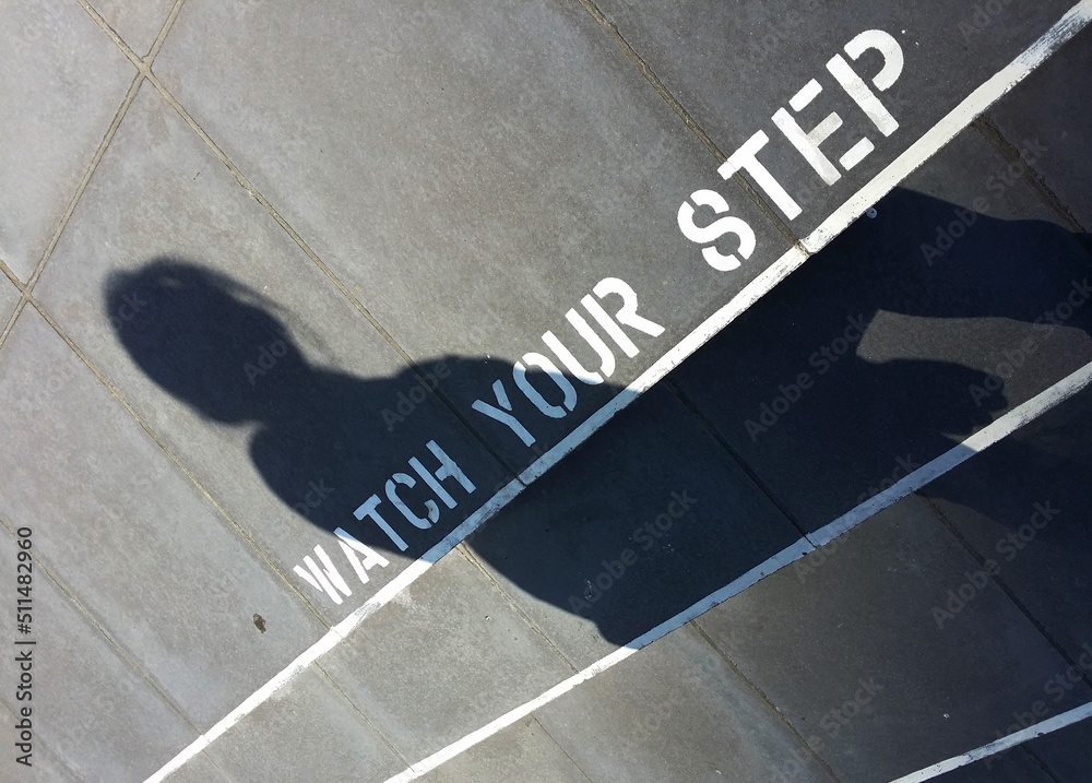 Watch your step marking on the ground with shadow of a walking lady ...