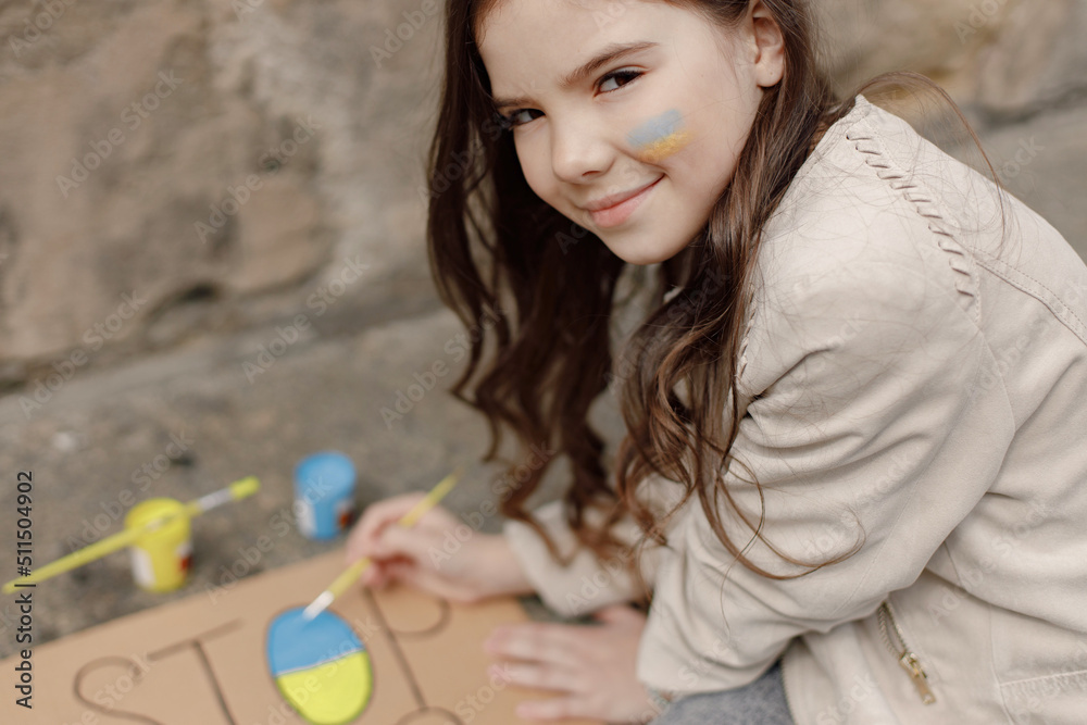 Poster Little girl with a flag of Ukraine on a cheek draw a poster ...
