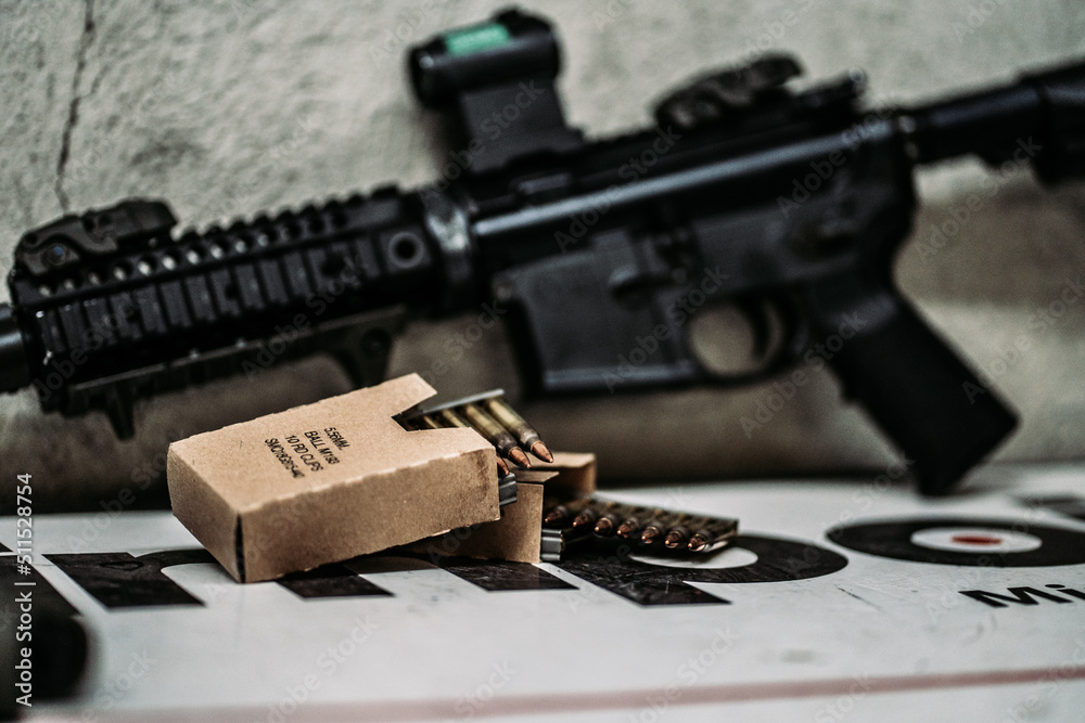 Assault rifle with red dot sight next to a box with ammunition Stock ...