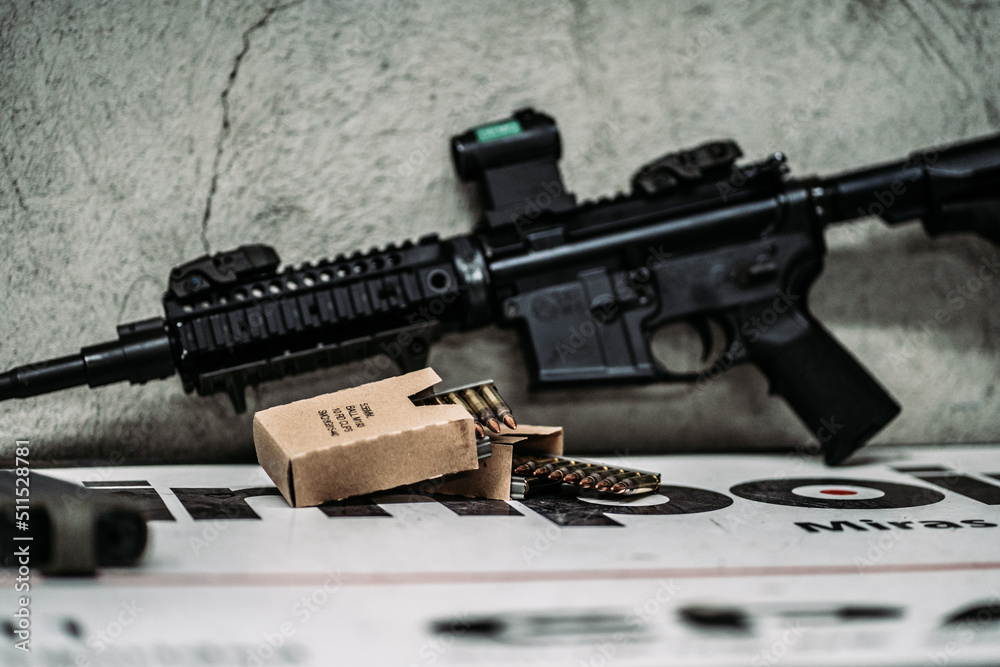 Assault rifle with red dot sight next to a box with ammunition Stock ...