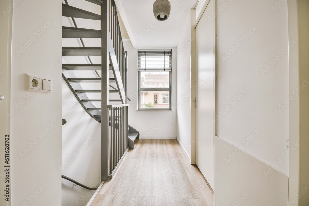 A window next to a gray spiral staircase connecting the floors of a ...