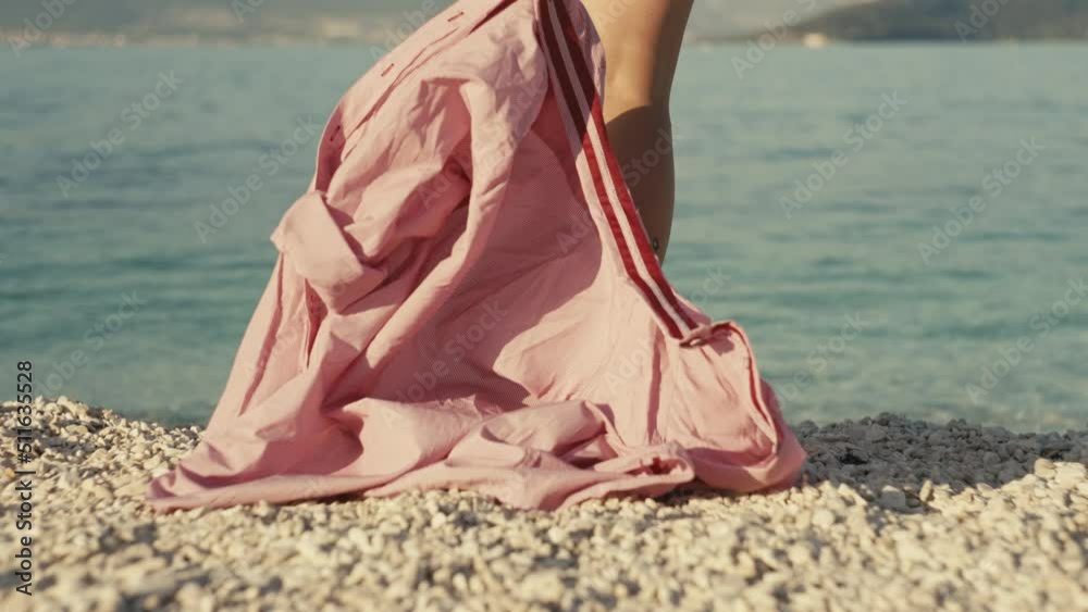 Slow motion video of a girl taking off her shirt and going into the sea ...