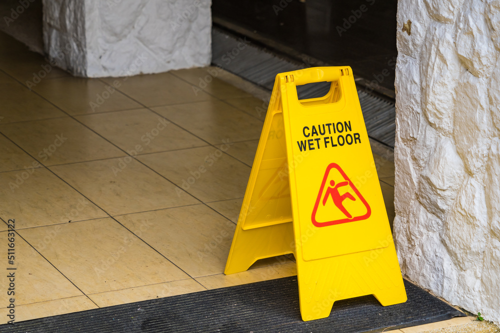 Wet floor caution sign on walkway near the building after raining ...