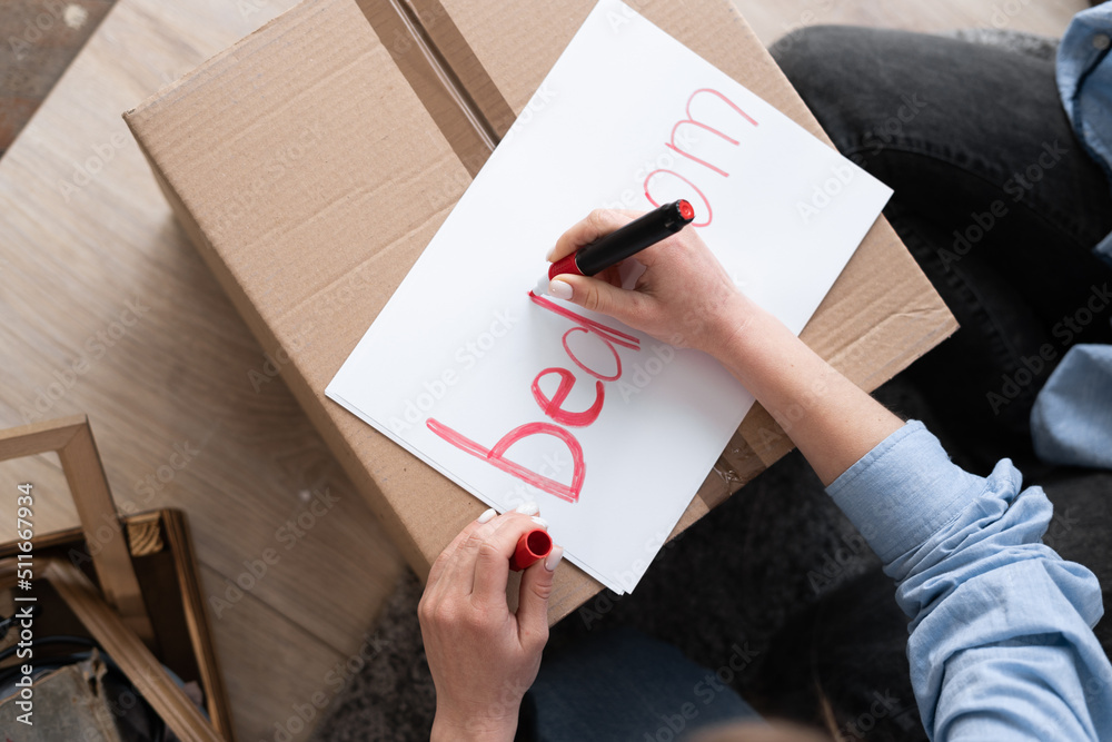 preparing boxes for moving, top view of hand signing big box, moving ...