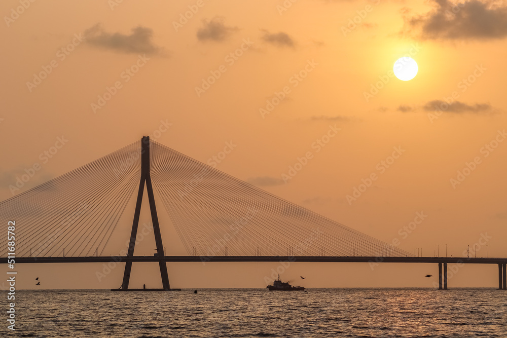 sunset near mumbai worli bandra sea link bridge and small boat in ocean ...