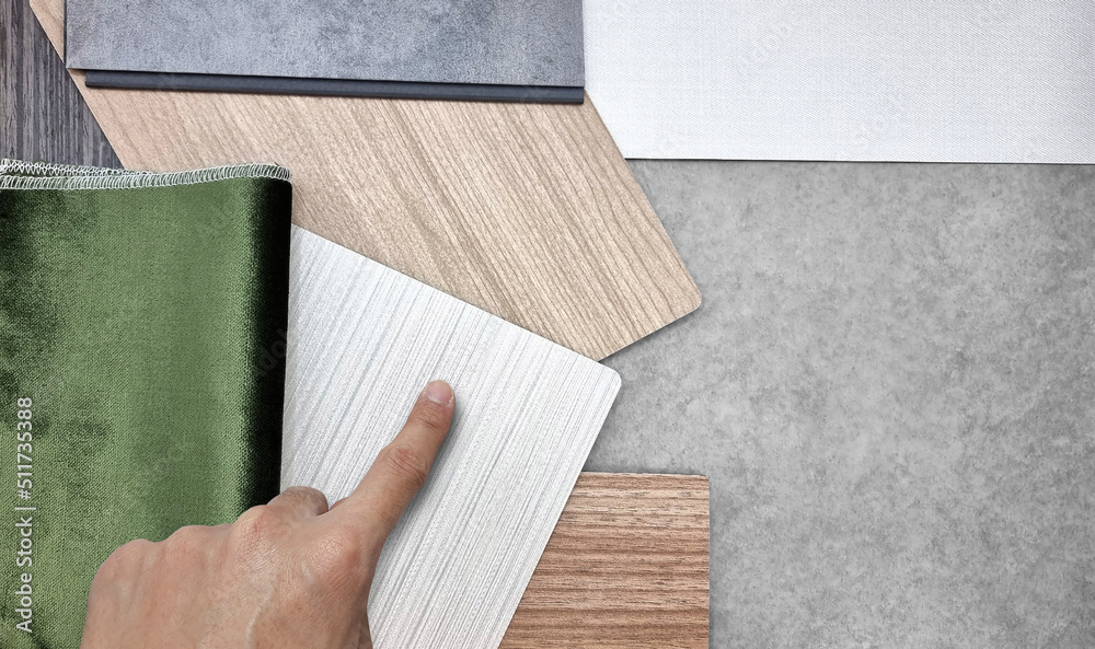 designer's hand selecting to interior material samples containg green ...