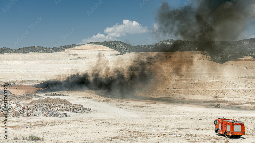 Fire fighting in a tire dump. Fire truck and black smoke from burning ...