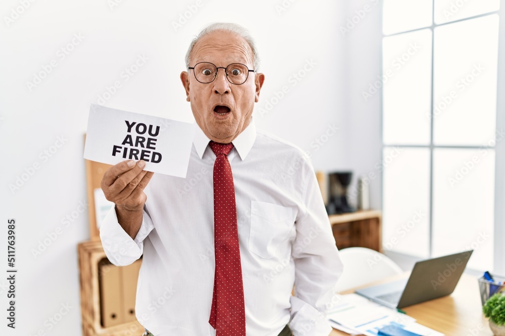 Senior business man holding you are fired banner at the office scared ...