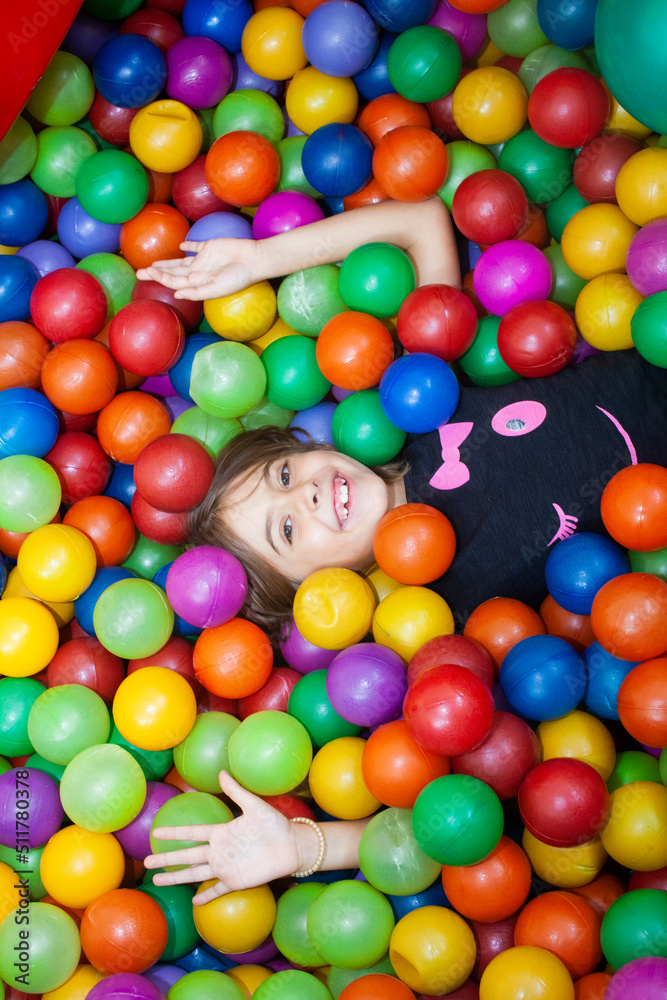 young happy girl covered in colorful plastic balls in a ball pit Stock ...