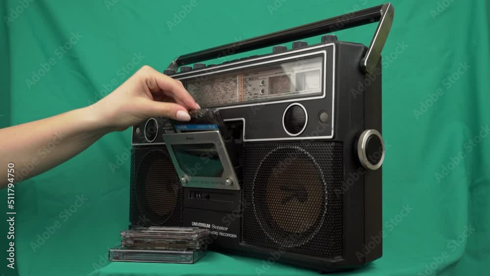 Girl takes out a vintage cassette into a black radio tape recorder on a ...