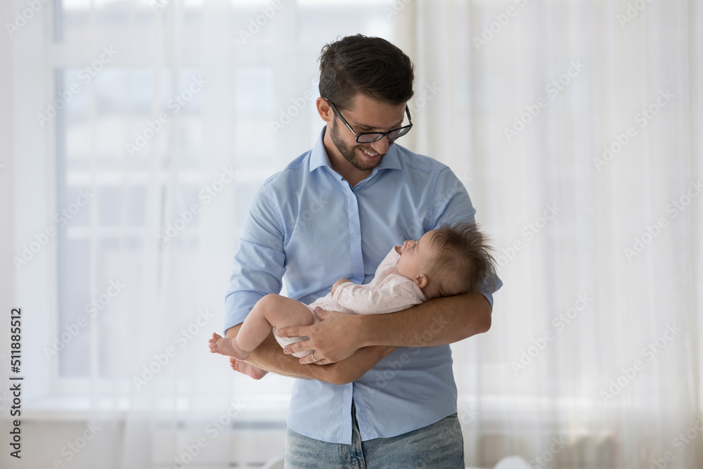 Young caring daddy holding on arms his infant baby daughter, looking ...