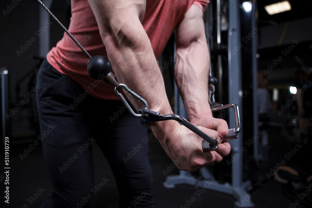Muscular arms with veins close up, bodybuilder exercising in cable ...