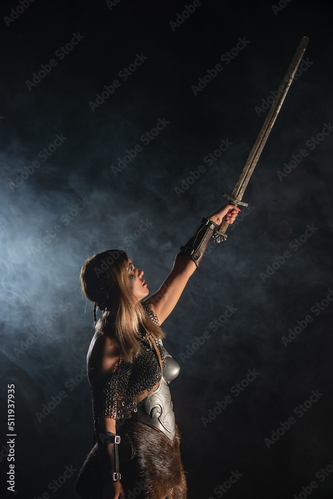 Warrior woman in the armor stands with the raised up sword. Victory ...