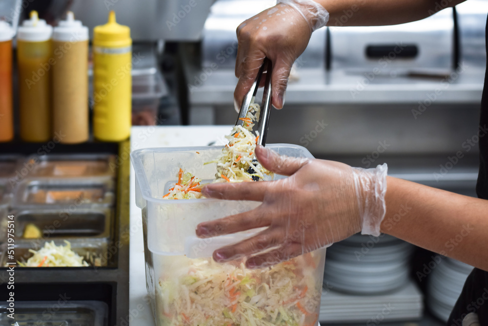 Restaurant kitchen employee restocking food station with coleslaw Stock ...