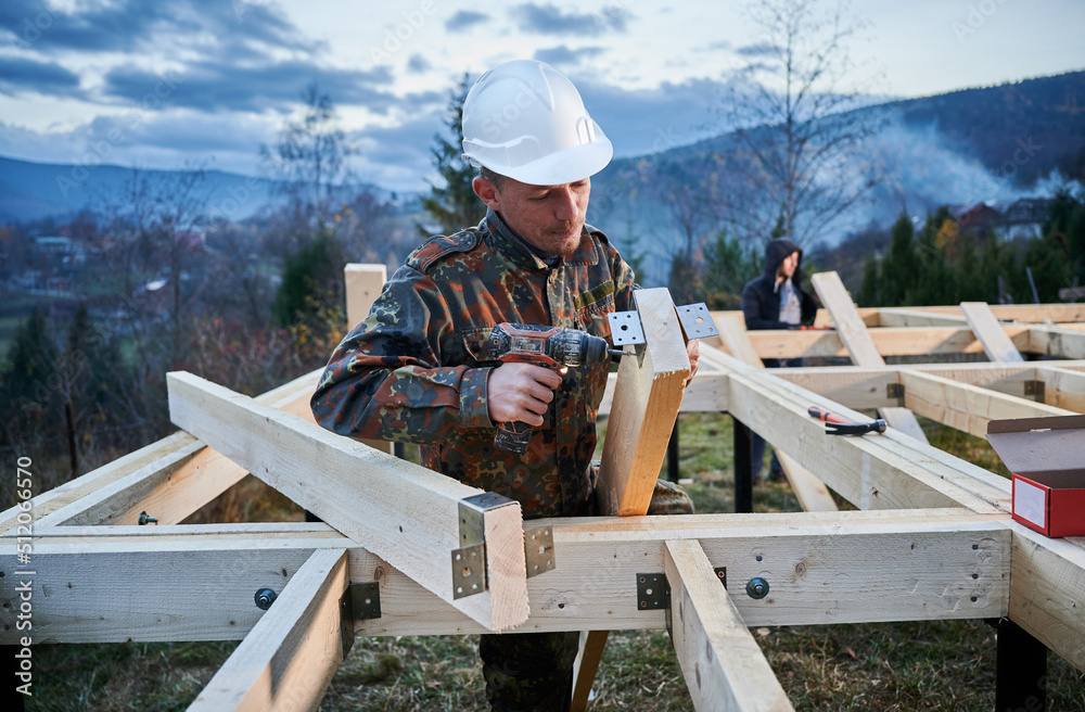 Man worker building wooden frame house on pile foundation. Carpenter ...