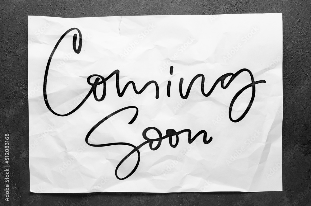 Coming soon. Lettering on crumpled white paper. Handwritten text ...