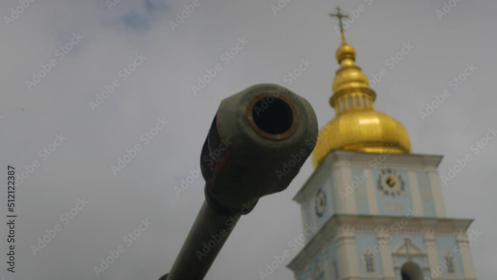 Close up of silenced tank barrel with golden church dome in background ...