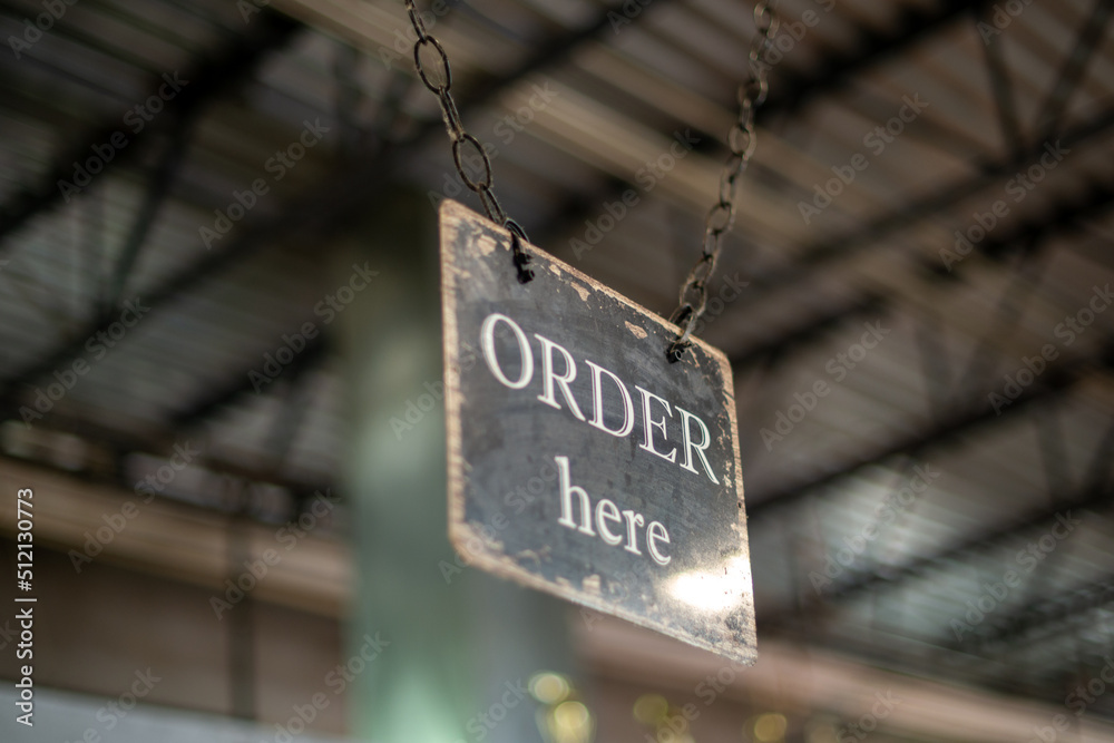 An order here sign made of metal with white letters on a black ...
