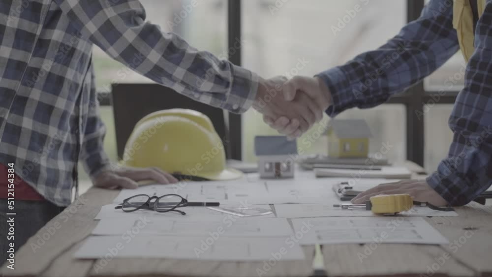Two Civil Engineer or Architect holding helmet and handshaking after a ...