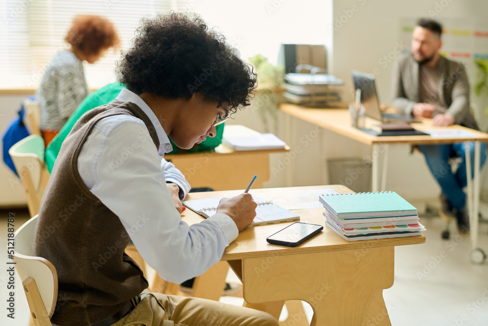 Highschool student in smart casualwear making notes in copybook at ...