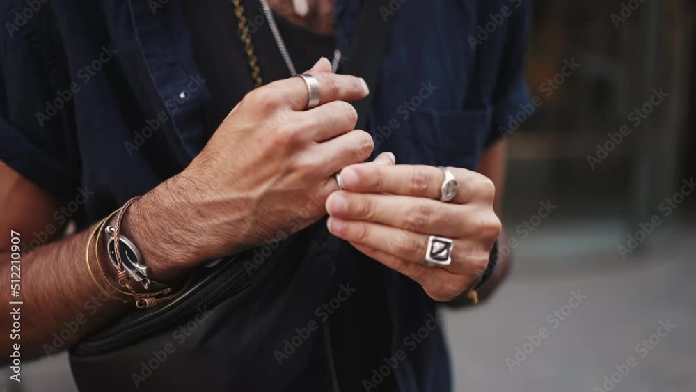 Close-up of male hands in bracelets and rings. Man adjusts the ring on ...