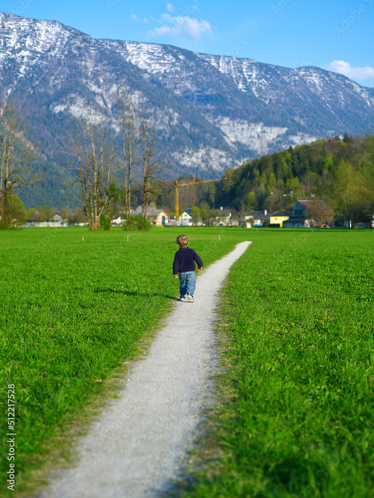 Foto de Little boy walking alone along pathway in the field. Path in ...