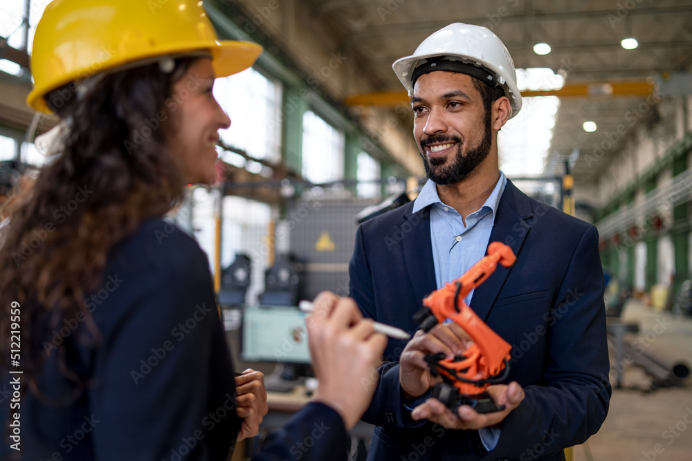 Man engineer holding model of industrial robotic arm and showing to ...