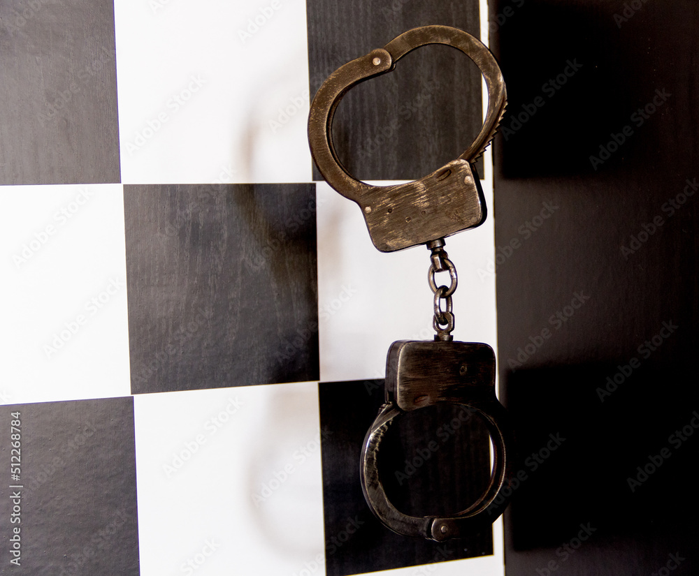 Handcuffs on the background of a concrete wall and a shadow from them ...