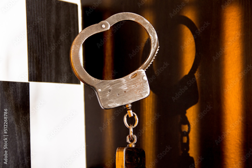 Handcuffs on the background of a concrete wall and a shadow from them ...
