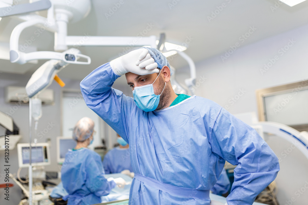 Tensed surgeon with hands on face in operating room in hospital ...