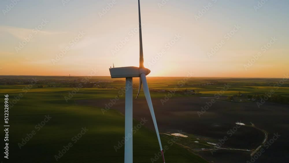 Drone flying close up to wind turbine nose cone to show a field of ...