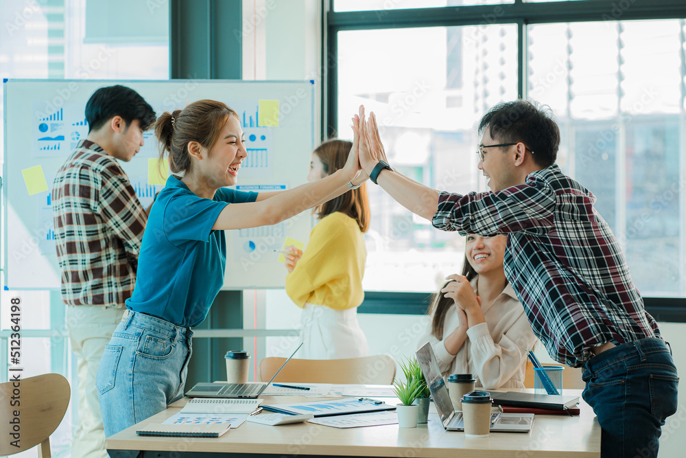 A group of creative young Asians in casual wear join hands to celebrate ...