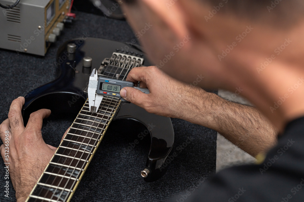 Latin American luthier calibrates the strings of an electric guitar ...
