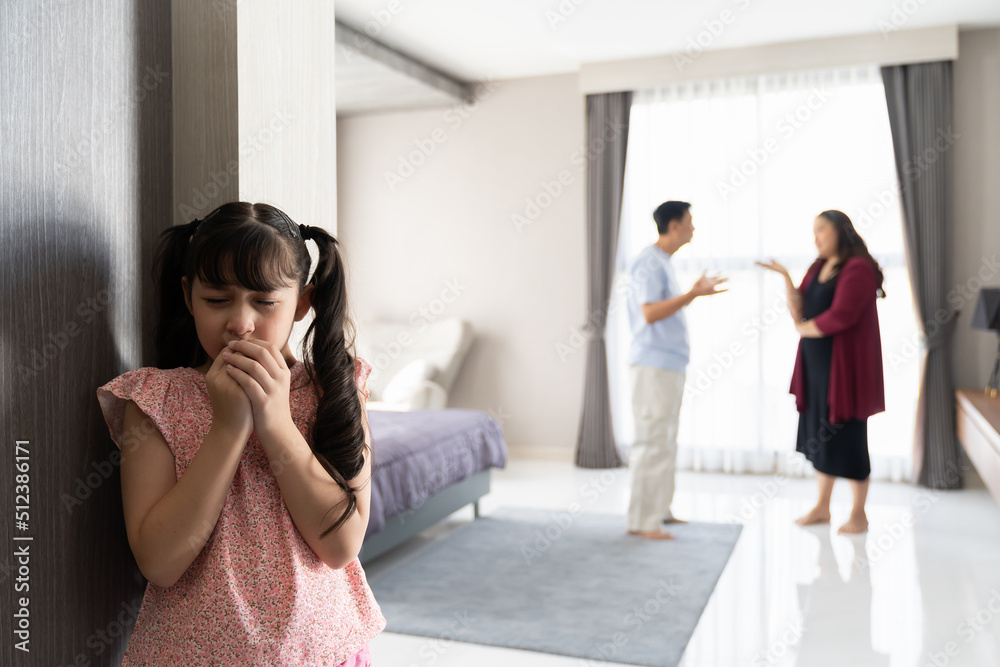 Child girl crying at the door from father and mother arguing. Little ...