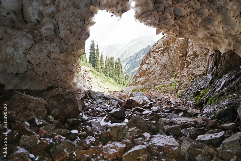 Ice grotto, a snow cave in the mountains in summer. Drops drip from the ...